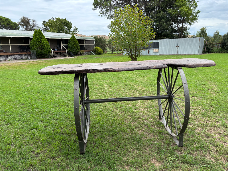 Lot 43 - Red gum timber slab table, mounted on steel wheel ends ...